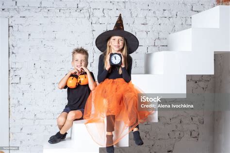 소름 끼치는 마녀 의상과 모자를 쓴 아이들은 검은 색 알람 시계와 호박 모양의 바구니를 들고 있습니다 10월에 대한 스톡 사진 및 기타 이미지 Istock