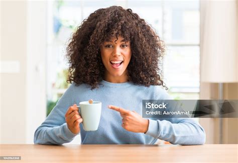손과 손가락으로 가리키는 매우 행복 가정에서 커피 한 잔을 들고 아프리카계 미국인 여자 가리키기에 대한 스톡 사진 및 기타 이미지 가리키기 감정 곱슬 머리 Istock