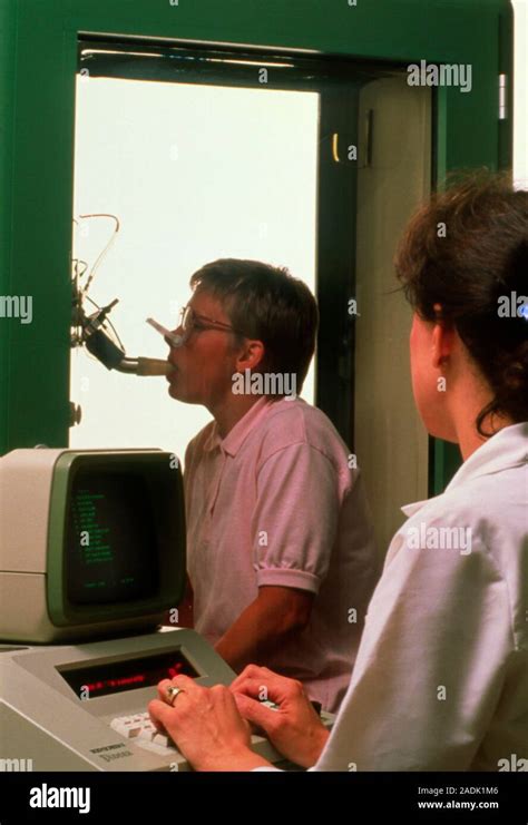 Testing Lung Function A Woman Breathing Into A Peak Flow Meter Background Has Her Lung