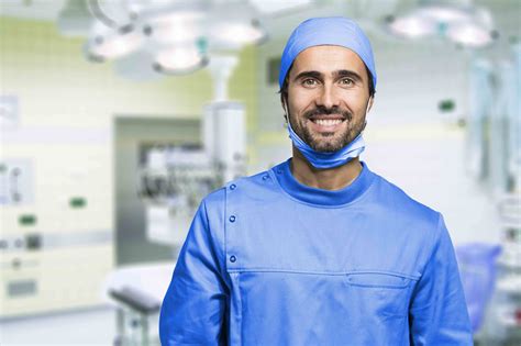 Smiling Surgeon Crossing His Arms While Standing In A Surgical R IDMED