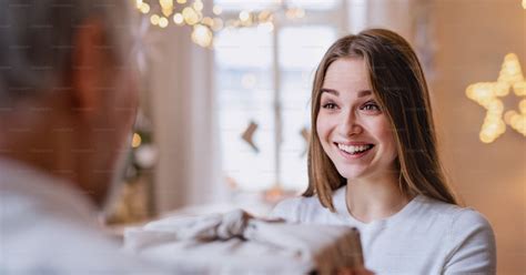 크리스마스에 집에서 알아볼 수 없는 할아버지로부터 선물을 받는 놀란 젊은 여성 사진 Unsplash의 슬로바키아 이미지