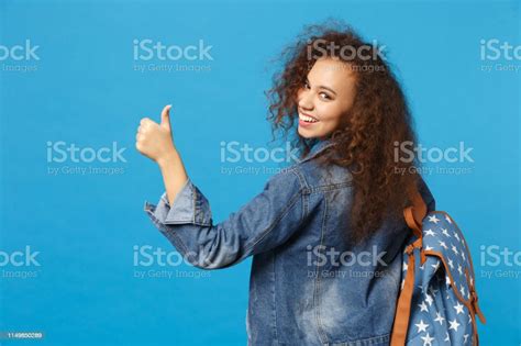 데님 옷에 젊은 아프리카계 미국인 소녀 사춘기 학생 배낭은 파란색 벽 배경 스튜디오 초상화에 고립 된 책을 잡아 고등학교 대학 대학 개념에서 교육 복사 공간을 모의 가방에