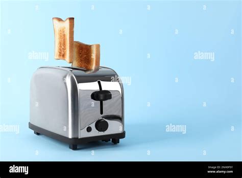 Bread Slices Popping Up From Modern Toaster On Light Blue Background Space For Text Stock Photo