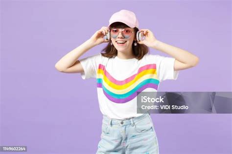 생생한 옷에 매력적인 십 대 소녀 심장 안경 스튜디오에서 보라색 파스텔 벽 배경에 고립 된 헤드폰으로 음악을 듣습니다 사람들은 진심으로 감정 라이프 스타일 개념입니다 복사