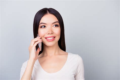 회색 배경 위에 서 클라이언트와 스마트 폰에 말하기 캐주얼 옷에 예쁜 매력적인 웃는 여자의 초상화를 닫습니다 고객에 대한 스톡