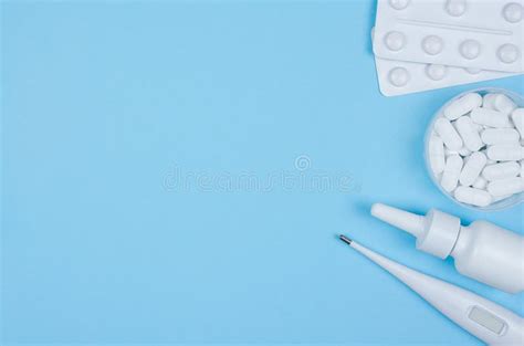 Blisters With Tablets A Thermometer And Nasal Spray On Blue