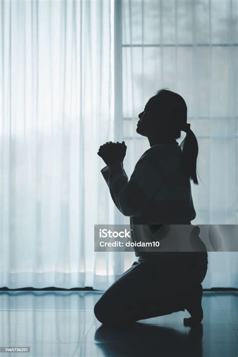 일몰 시간에 현대 교회에서 무릎을 꿇고 기도하는 여자의 실루엣 하느님께 드리는 여성 가톨릭 기도 예배는 믿음으로 새벽에 가정에서