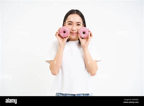Beautiful Young Woman Eating Delicious Glazed Dougnuts Holding Two