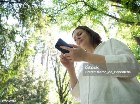젊은 여자는 봄에 나무로 둘러싸인 자연에서 전화를 사용합니다 30 34세에 대한 스톡 사진 및 기타 이미지 30 34세