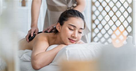 아시아 젊은 여성은 행복을 느끼고 기름으로 등 마사지를하는 동안 휴식을 취합니다 마사지 테이블에 누워 있는 매력적인 아름다운