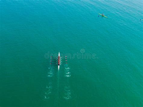 Aerial View Of Rowing Team On Vibrant Blue Water A Single Rower Is