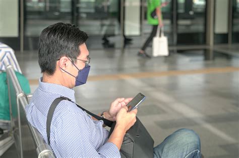 기차 플랫폼에서 기다리는 얼굴 마스크를 착용한 사업가 마스크 된 대중 교통 개념 Brand Name Smart Phone에 대한