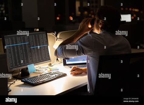 caucasian male programmer sitting at desk drinking coffee using