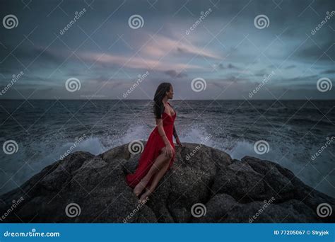 Beautiful Seductive Woman In Red Dress Enjoying Herself On Rocks By The