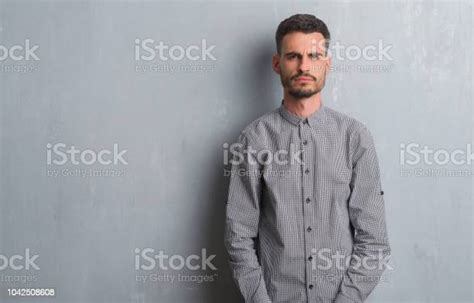 젊은 성인 남자 서 있는 회색 그런 지 벽 의심과 긴장 인상을 찌 푸 리고 문제 때문에 화가 부정적인 사람입니다 감정에 대한