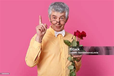 매력적인 수석 남자의 이미지 앞에 제기 되 면 아이디어를 주고 꽃 손가락 Transprent 시력 교정 안경을 착용 노란색