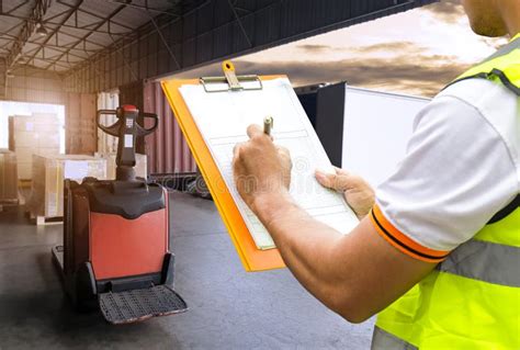 Warehouse Worker Holding Clipboard Checking On Checklist For Loading Shipment Goods Into