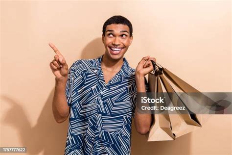 잘 생긴 꿈꾸는 남자가 옷을 입은 프린트 셔츠를 들고 흥정을 들고 빈 공간을 찾고 고립 된 베이지 색 배경을 보여주는 사진 18 19세에 대한 스톡 사진 및 기타 이미지