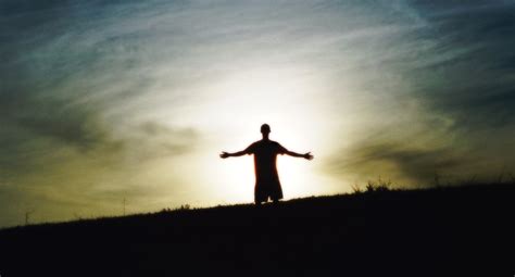 Silhouetted Figure With Outstretched Arms Against Bright Sky Free Stock