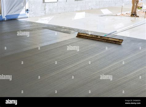An Employee Of Construction Company Uses Broom To Surface Of Fresh Wet