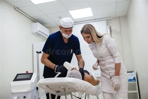 Doctor Cosmetologist Teaches A Young Trainee Blonde The Procedure Of Laser Hair Removal At The