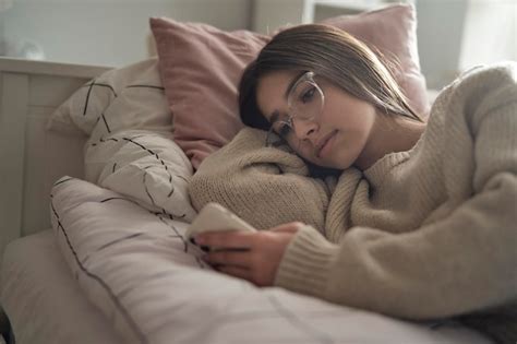 Premium Photo Caucasian Teenage Girl Browsing Phone While Lying On Bed