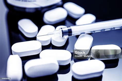반사 표면에 주사기가 있는 흰색 알약의 클로즈업 보기 약물 투여를 설명하는 제약 개념 0명에 대한 스톡 사진 및 기타 이미지