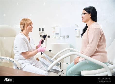 Experienced Gynecologist Talking With Adult Asian Patient About Her