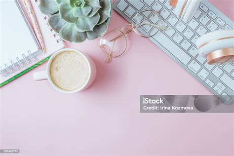 분홍색 배경에 커피 즙이 많은 노트북 빈 노트북 헤드폰 키보드 및 황금 안경을 갖춘 사무실 여성용 책상 작업 공간 맨 위 보기