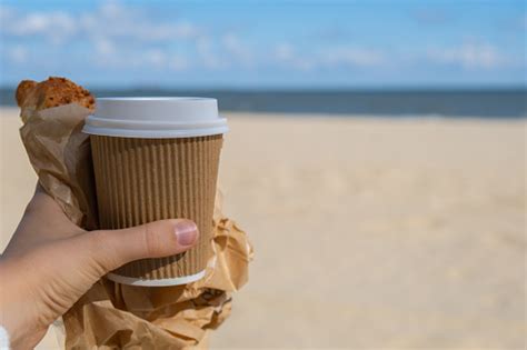 해변 바다 배경에 여성 손에 종이컵에 커피를 곁들인 맛있는 신선한 크로와상 야외 아침 식사 웰빙 개념 증권 시세 표시기 음식을 가져 가라 커피 마실 것에 대한 스톡 사진 및