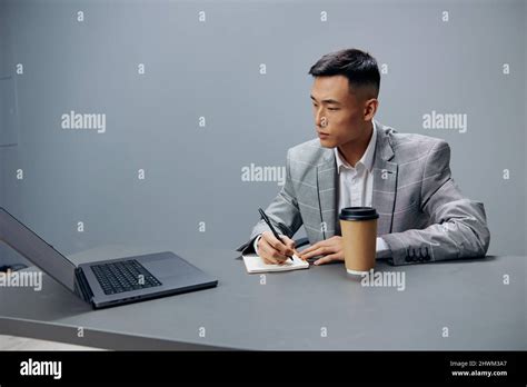Asian Man Writing In A Notebook Laptop Work At The Desktop Lifestyle