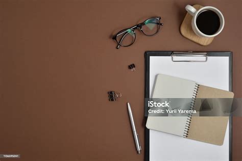 빈 클립 보드 사무 용품 펜 커피 컵 메모장 및 갈색 배경에 안경 작업 공간을 모의 플랫 레이 평면도 복사 공간 0명에 대한