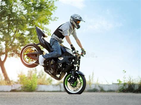 O Motociclista Está Levantando Sua Motocicleta Durante O Por Do Sol Imagem de Stock