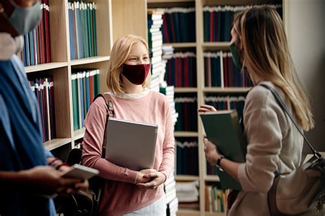 도서관에서 말하는 보호 얼굴 마스크와 행복한 대학 친구 Covid 19에 대한 스톡 사진 및 기타 이미지 Covid 19