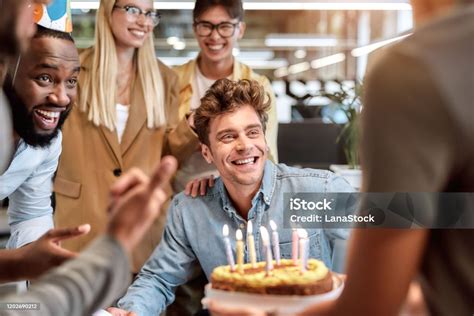행운을 빌며 웃는 혼합 인종 사업사람들 사이에서 생일을 축하하면서 케이크에 촛불을 부는 젊은 행복한 남자 생일에 대한 스톡 사진 및 기타 이미지 Istock