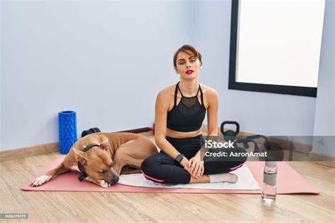 요가 매트에 앉아 있는 젊은 아름다운 여자는 얼굴에 진지한 표정으로 긴장을 풀고 있다 카메라를 보는 간단하고 자연스러운 모습 사람 얼굴에 대한 스톡 사진 및 기타 이미지
