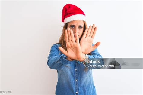 고립 된 배경 을 통해 크리스마스 모자를 입고 젊은 아름다운 빨간 머리 여자 거부 표정 횡단 팔과 손바닥을하고 부정적인 기호 화가 얼굴 개념에 대한 스톡 사진 및 기타