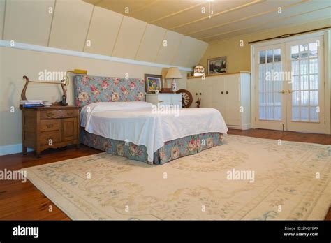 Grand lit double avec couvre lit blanc et tête de lit en tissu fleuri tables de nuit roue