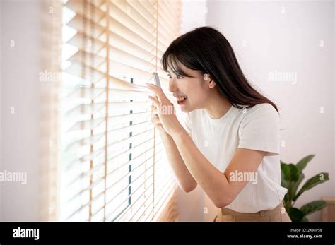 A Curious Nosy Young Asian Woman Spying On Neighbor From Window