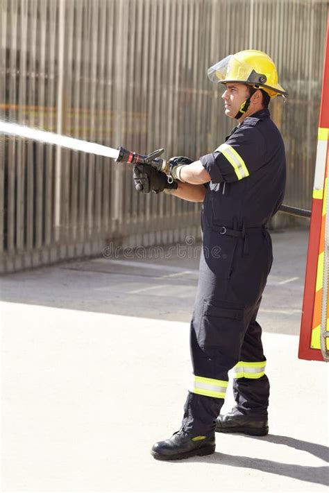 Male Firefighter Spray Water And Emergency Worker With Helmet Uniform