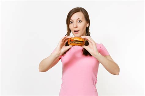 분홍색에서 젊은 아름 다운 여자 T셔츠에 머리 띠와 흰색 배경에 고립 햄버거 손 적절 한 영양 섭취 또는 고전적인 미국의 패스트 푸드입니다 광고에 대 한 공간을 복사 합니다