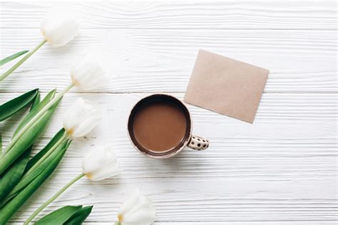 흰색 나무 소박한 배경 텍스트를 위한 공간으로 커피 공예 인사말 카드와 튤립 꽃과 음료와 빈 종이와 세련 된 플랫 하다