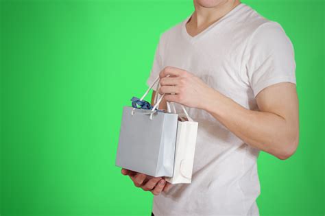 손으로 들고 있는 남자는 두 개의 종이 선물 가방을 모의로 두 개 들고 있었다 빈 패키지 모형은 격리 된 손에 잡습니다 로고