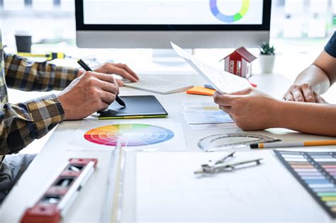 그래픽 태블릿과 현대 사무실에서 작업 색상 시계에 스케치 젊은 인테리어 그래픽 디자이너 작업 하우스 프로젝트의 팀 디자인 창조적