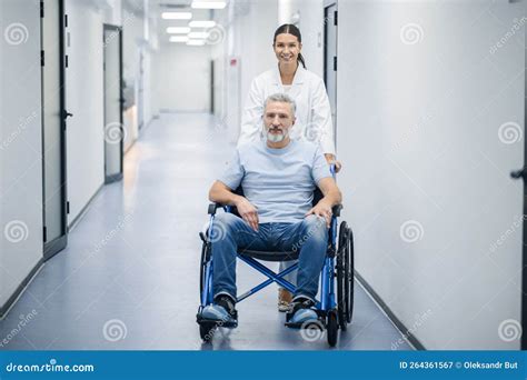 Dark Haired Nurse Carrying The Wheelchair With A Patient Stock Image