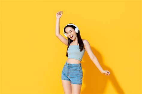 여름에 행복한 젊은 아시아 여성은 헤드폰에서 음악을 듣고 노란색 배경에 고립 된 춤을 착용 춤에 대한 스톡 사진 및 기타 이미지