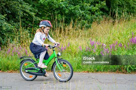 자전거를 타는 어린 미취학 소녀 야외에서 자전거를 탄 아이 따뜻한 여름날 학교에 가는 길에 자전거 타기를 즐기는 행복한 아이 안전한 헬멧을 쓰고 자전거에서 균형을 잡는 법을