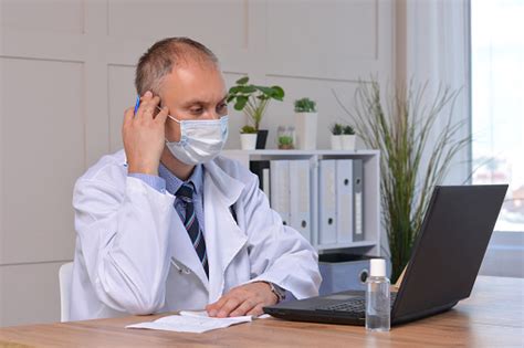 코로나바이러스의 발병으로부터 보호하기 위해 의료용 마스크를 쓰고 환자에게 처방전을 쓰는 의사의 초상화 공공 혼잡 한 장소에서 바이러스 및 질병 보호 손 소독제 Brand