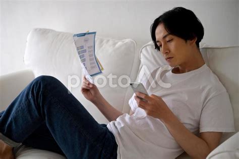 ソファーに座ってスマホを使う男性 No 4837219｜写真素材なら「写真ac」無料（フリー）ダウンロードok