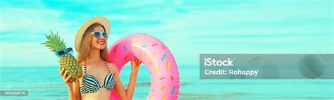 바다 배경의 해변에서 밀짚 모자를 쓰고 풍선 반지와 파인애플을 가진 행복한 미소 짓는 젊은 여성의 초상화 20 29세에 대한 스톡 사진 및 기타 이미지 Istock